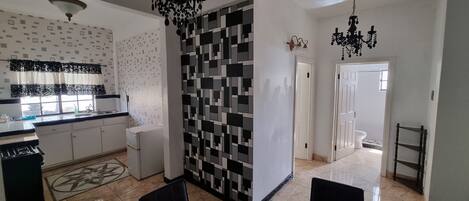 Cozinha moderna com painel decorativo atrás do fogão, área de refeições com mesa e cadeiras, e um lustre.