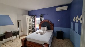 Quarto com cama, escrivaninha, cadeira, guarda-roupa e ar condicionado.