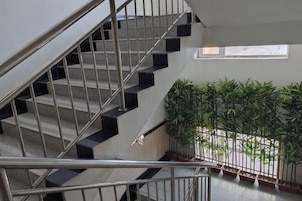 Escadaria com guarda-corpos de metal e parede com plantas em vasos.
