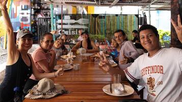 Um grupo de pessoas sentadas em volta de uma mesa de madeira, com pratos, copos e talheres.