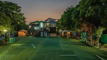 Um edifício moderno com telhado verde, área externa coberta e escadaria que leva a um andar superior.