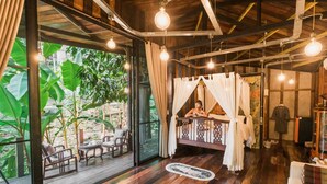Quarto com teto de madeira, janelas amplas e cama com dossel.