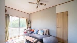 Uma sala de estar moderna com um sofá seccional cinza, uma mesa de centro de vidro e um ventilador de teto.