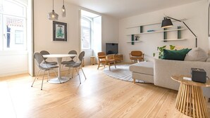 Uma sala de estar moderna com uma mesa de jantar redonda, duas cadeiras, um sofá, uma televisão e uma estante de livros.