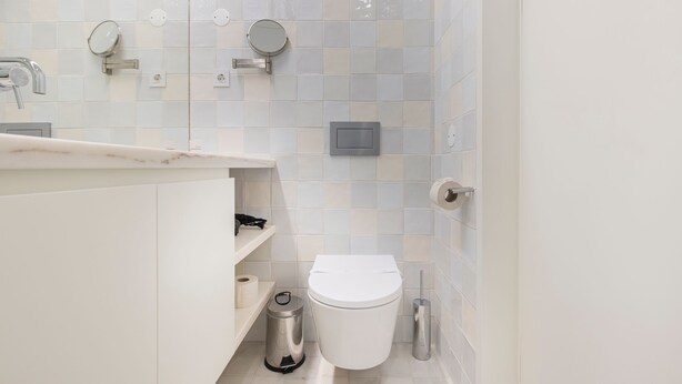Uma casa de banho moderna com sanita, bidé e um lixo.