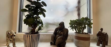 Um parapeito com três plantas em vasos e duas estatuetas de animais.