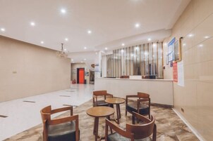 Um hall de hotel com recepção, área de estar e um lustre.