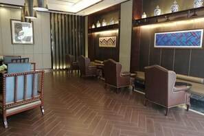 Um hall de entrada com balcão de recepção, áreas de estar e painéis decorativos nas paredes.