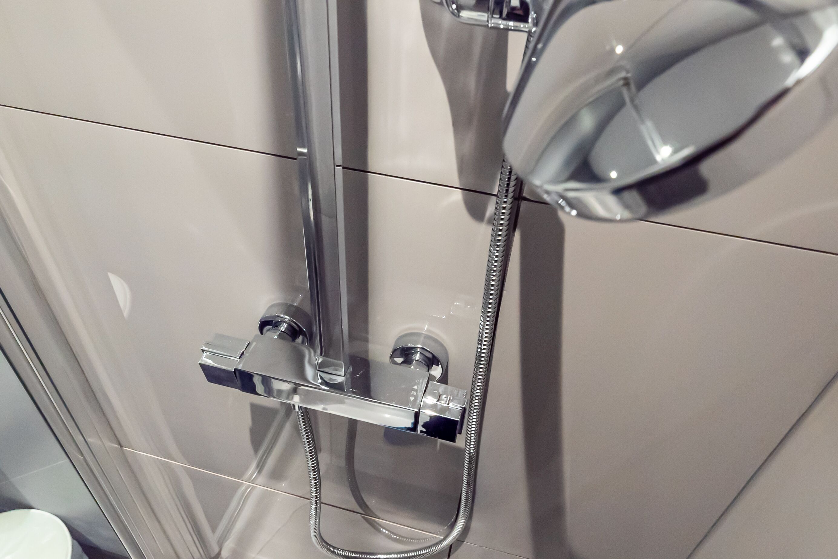 Uma casa de banho moderna com chuveiro envidraçado, acessórios em cromo e porta-toalhas visível.