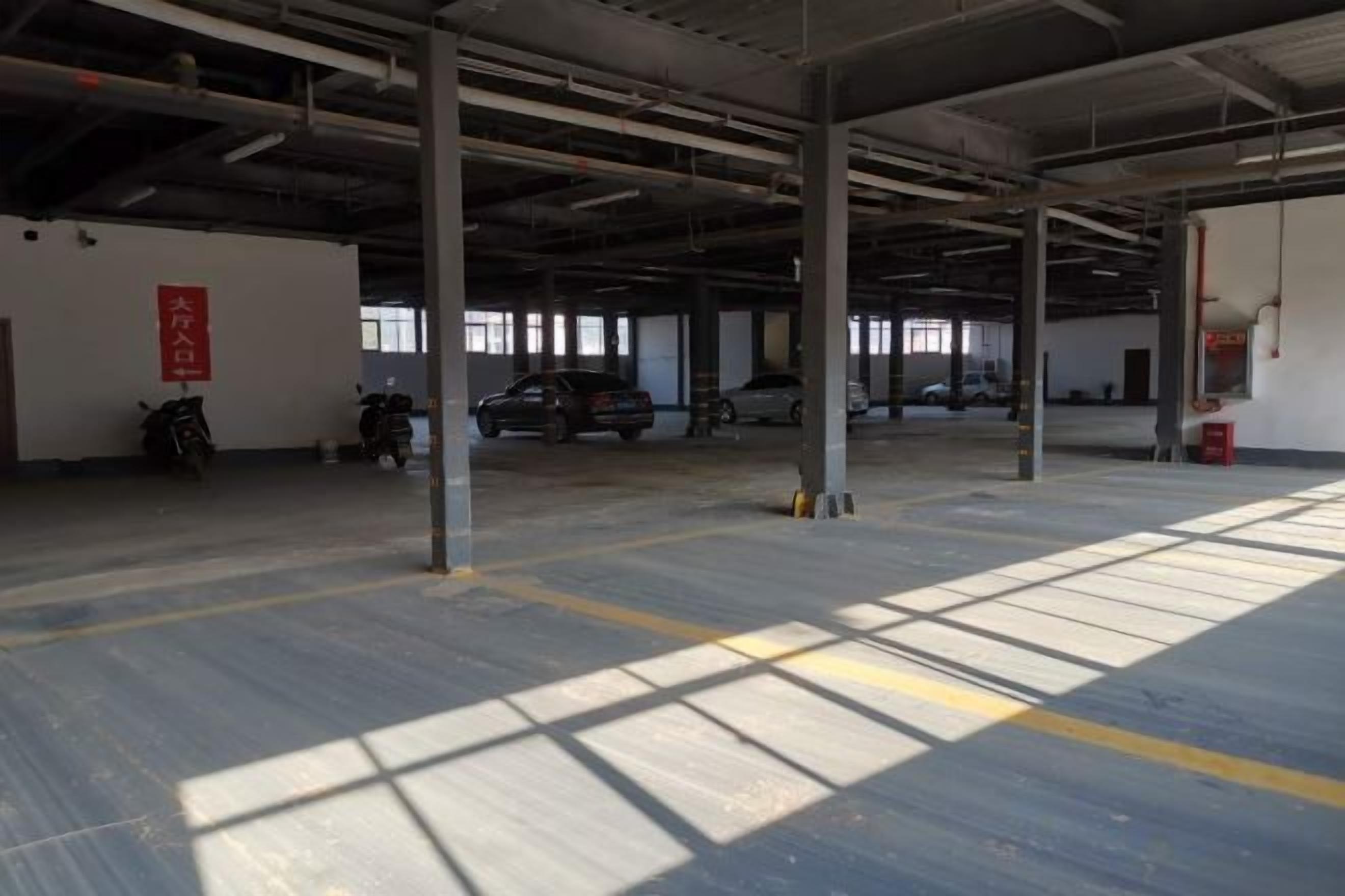 Garagem de estacionamento interna com vários níveis, pisos de concreto e colunas estruturais.