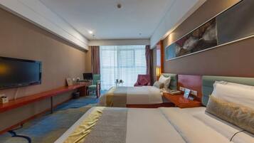Quarto de hotel com uma cama grande, televisão, escrivaninha e janela com cortinas.