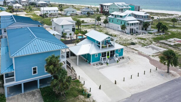 Uma área residencial costeira com casas, uma praia e vista clara para o oceano.
