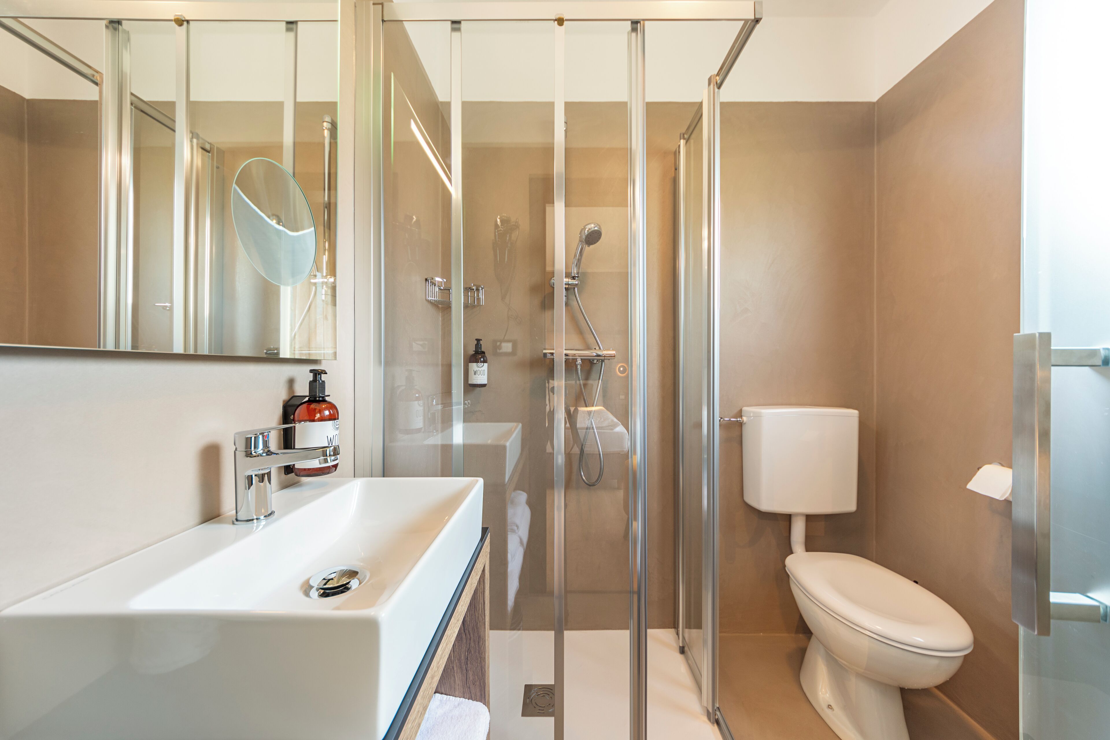 Uma casa de banho moderna com chuveiro envolto em vidro, lavatório branco e sanita.