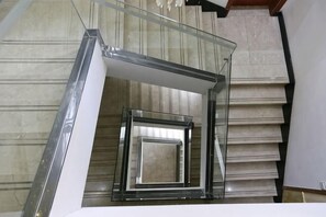 Uma escada moderna com guarda-corpos de vidro e azulejos bege.