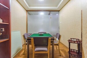 Quarto com mesa de bilhar, quatro cadeiras, um pequeno prateleira e um radiador.