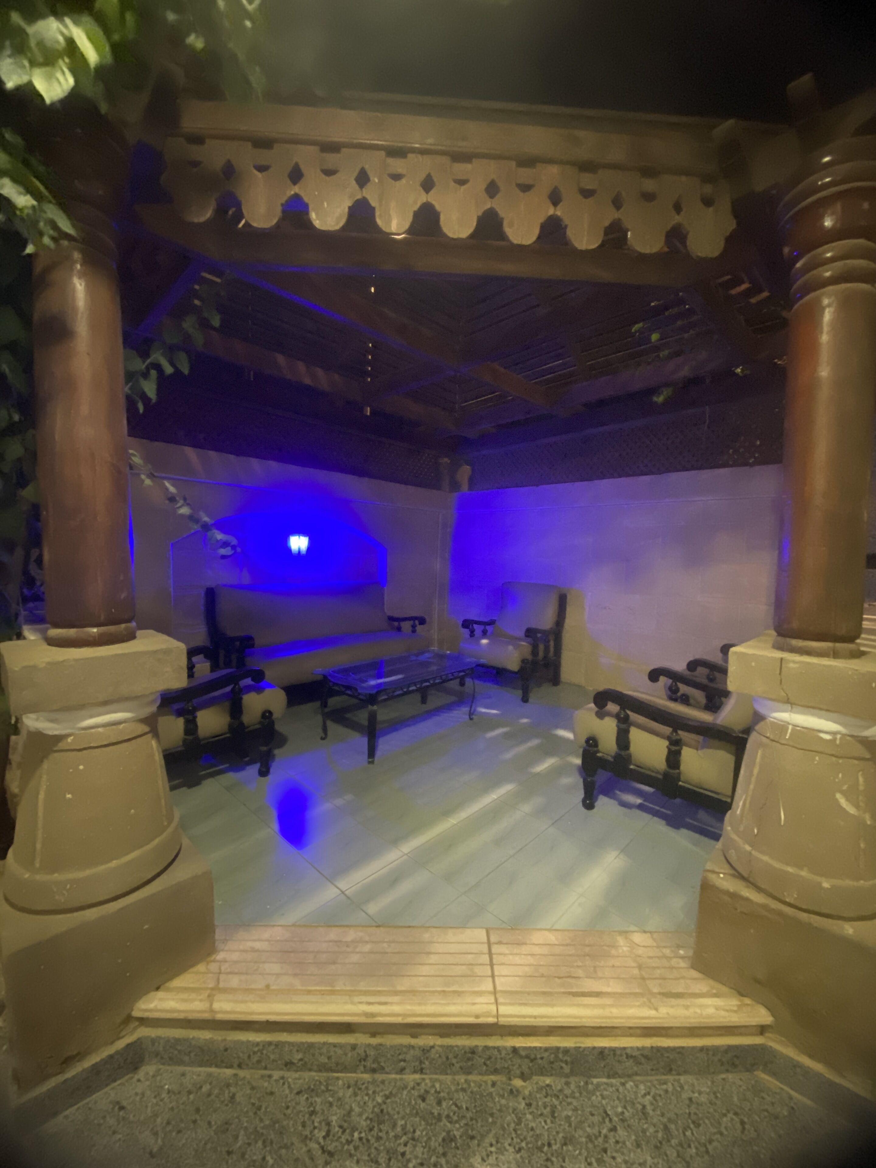 Um quarto com teto baixo, pilares de madeira e um espaço com bancos.