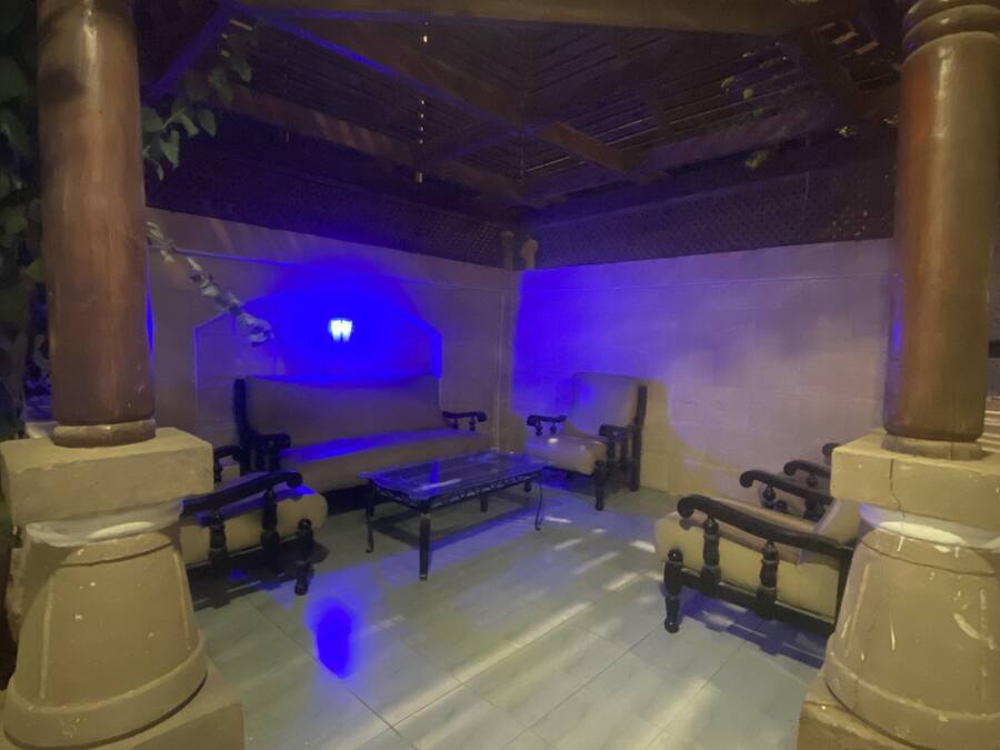 Um quarto com teto baixo, pilares de madeira e um espaço com bancos.