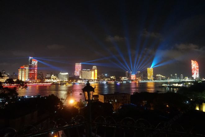 Paisagem urbana noturna com edifícios iluminados e um rio.