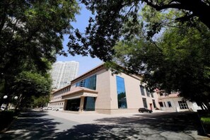 Um edifício com arquitetura moderna, grandes janelas e área de entrada pavimentada.