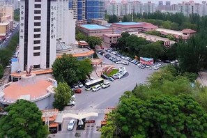Uma estrutura de estacionamento com vários níveis e um círculo de rotatórias central, rodeada por edifícios e áreas verdes.