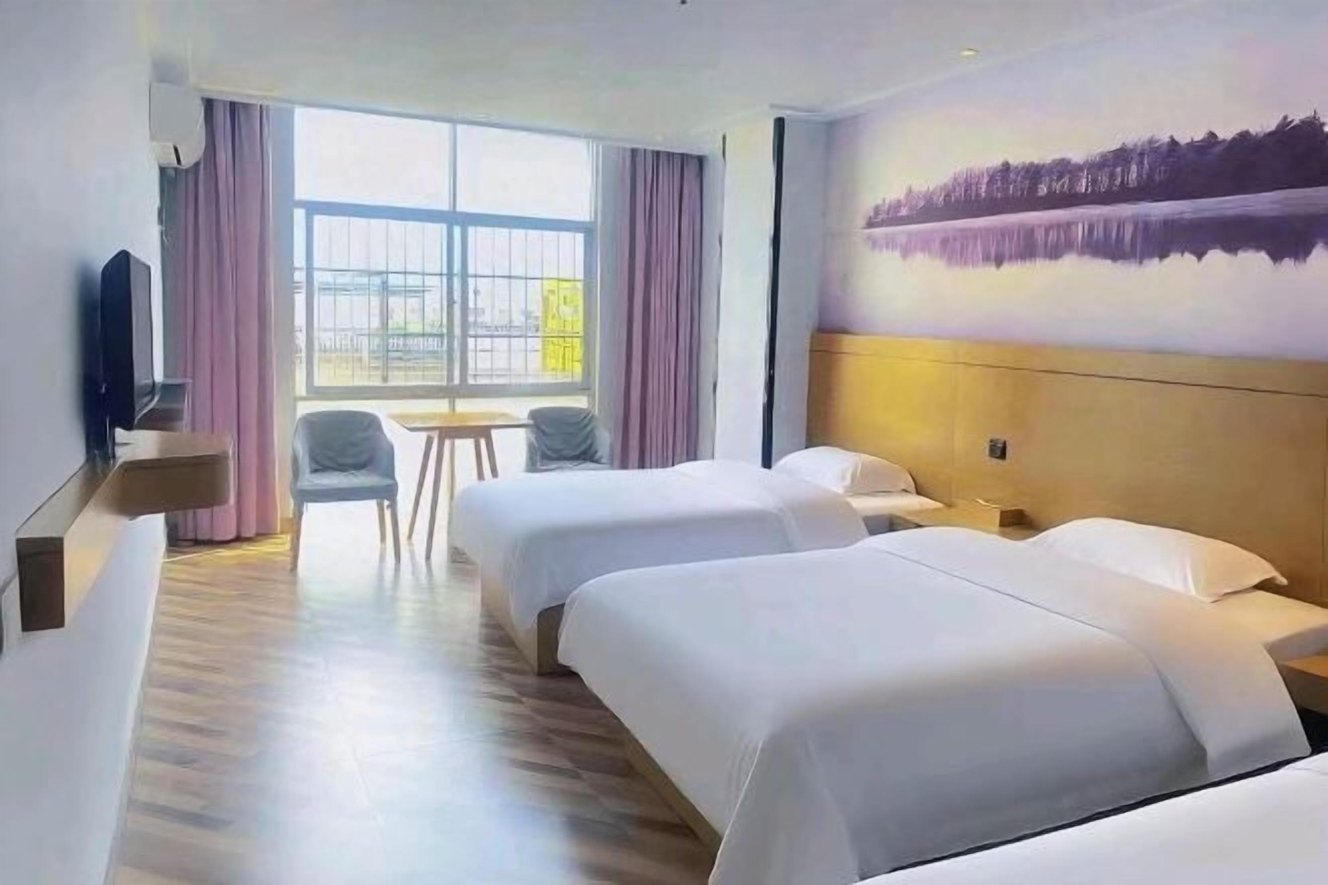 Quarto de hotel com duas camas, uma televisão, uma escrivaninha e uma cadeira.