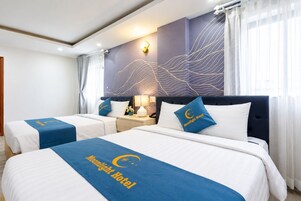 Quarto de hotel com duas camas, uma mesa de cabeceira, um abajur e uma parede com padrão ondulado.