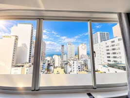 Paisagem urbana vista pela janela, com vários edifícios, incluindo um hotel com placa visível.