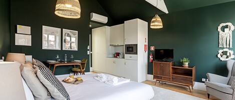 Quarto moderno com uma cama grande, uma escrivaninha e uma televisão.