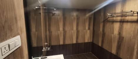 Um banheiro moderno com design de parede em madeira, pia branca e box de vidro.