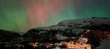 Montanha coberta de neve com um edifício iluminado em primeiro plano.