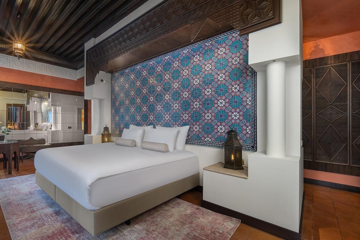 Quarto com uma cama grande, uma escrivaninha e uma cadeira. Há uma televisão no lado esquerdo do quarto.