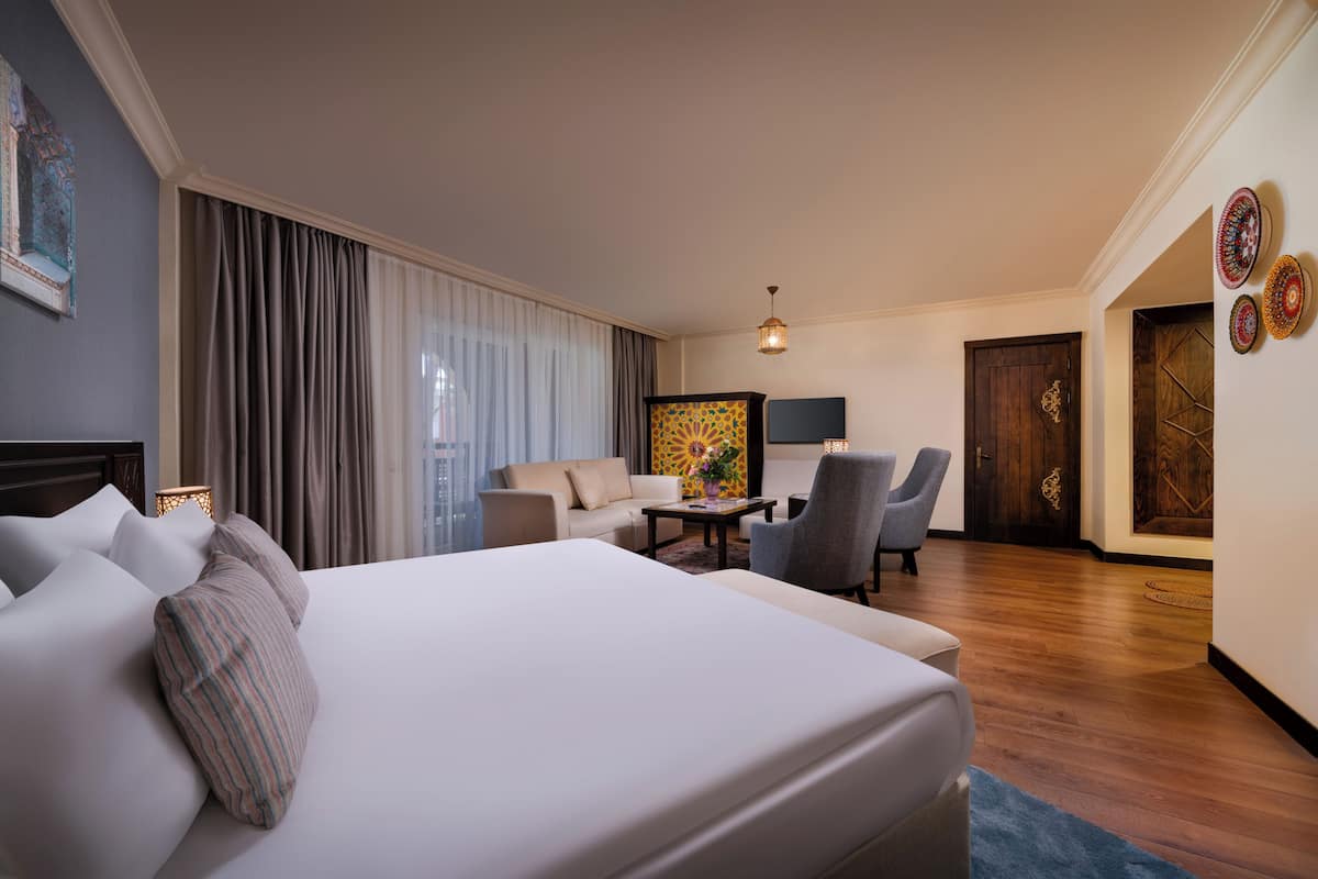 Quarto de hotel com uma cama grande, um sofá, uma escrivaninha e uma cadeira.