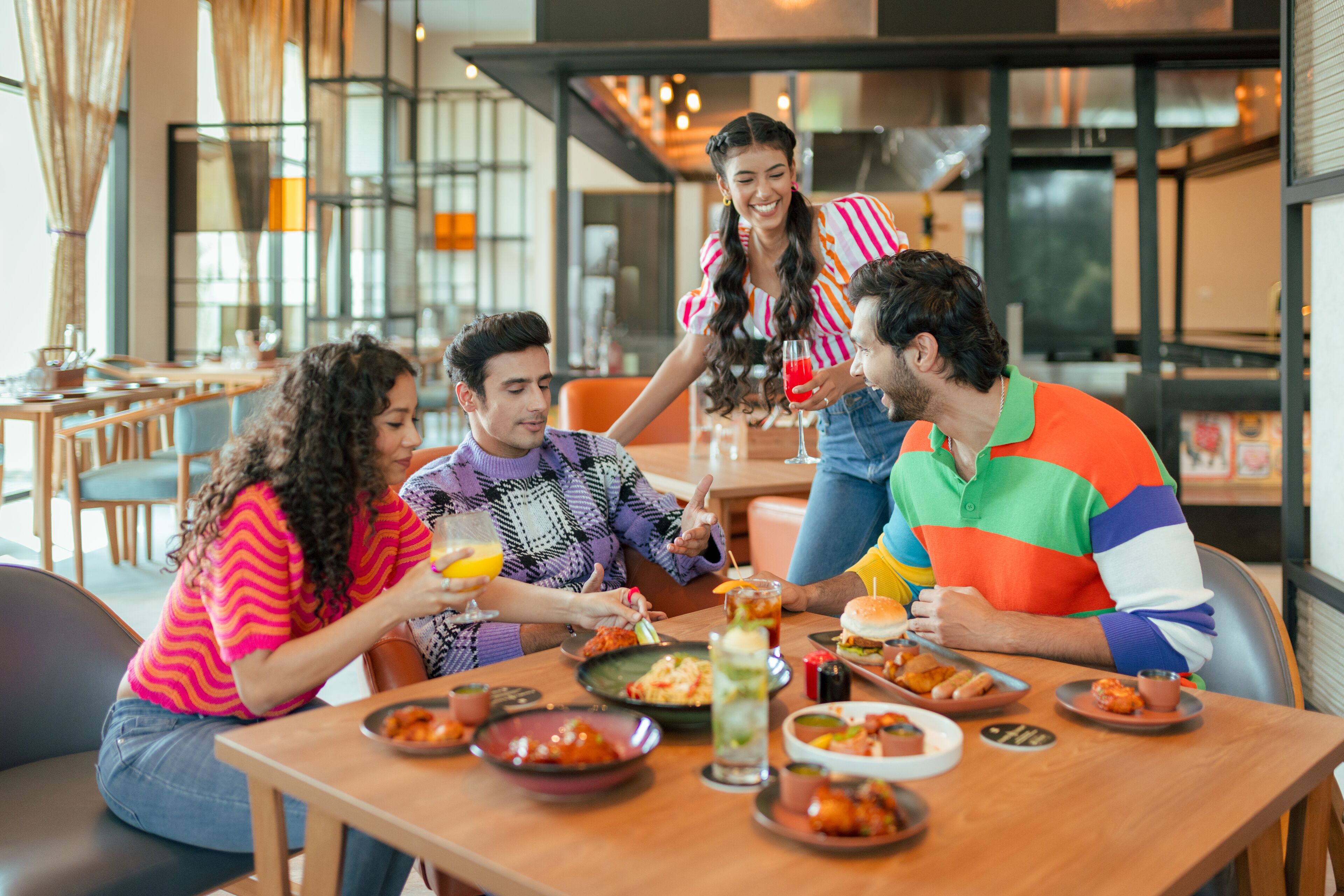 Um grupo de pessoas jantando em um restaurante, com diversos pratos e bebidas na mesa.