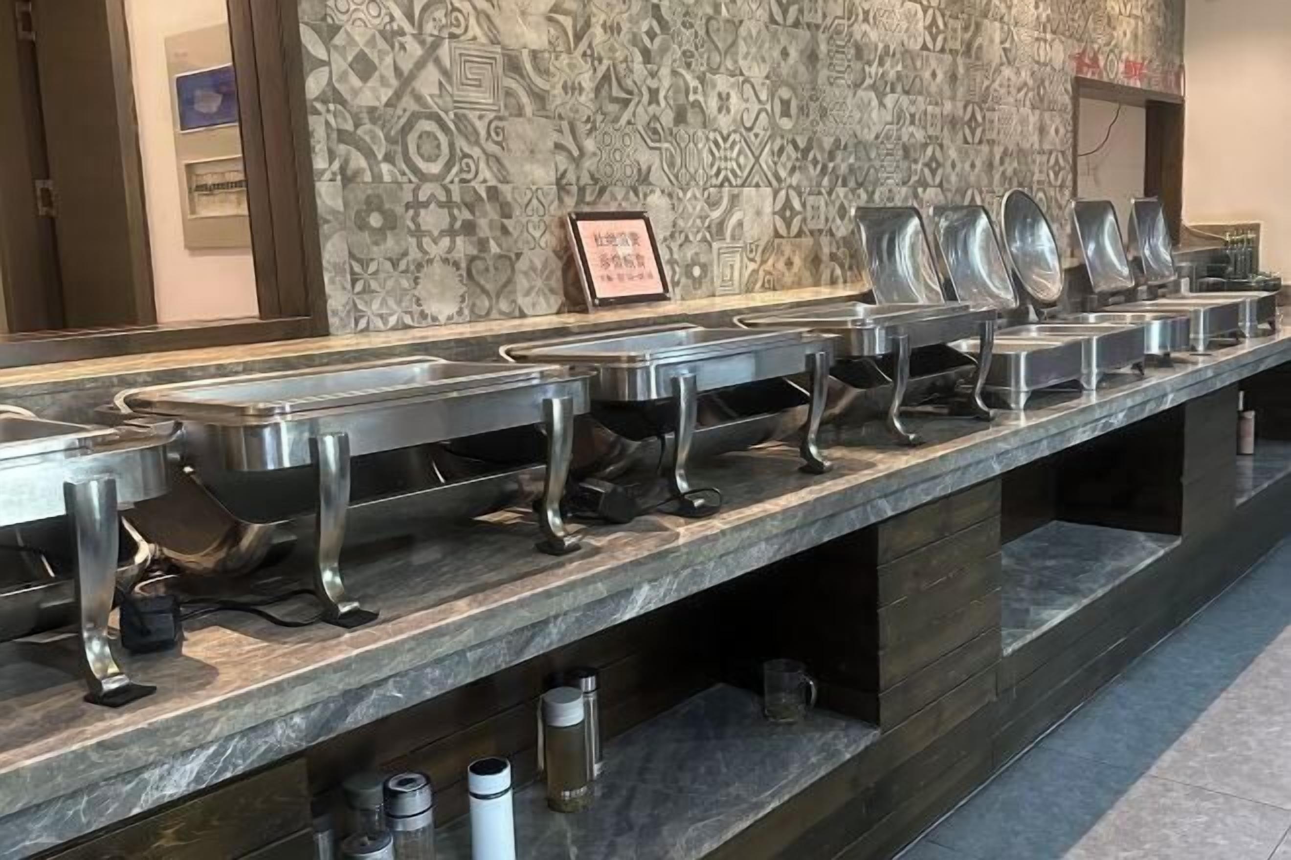 Disposição de buffet com várias estações de serviço e uma parede estampada ao fundo.