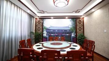 Sala de conferência com uma mesa redonda, cadeiras e vista para um edifício tradicional pela janela.