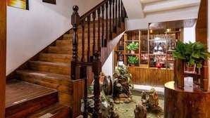Escadaria de madeira que leva a um quarto com um pequeno jardim interno e uma estante com plantas.