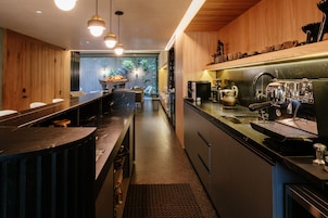 Cozinha moderna com detalhes em madeira, um balcão extenso e vista para uma sala de jantar.