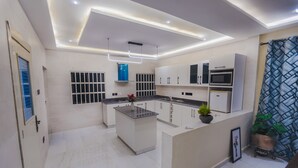 Cozinha moderna com armários brancos, ilha central e eletrodomésticos embutidos.
