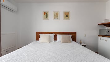 Quarto de hotel com cama, mesa de cabeceira, micro-ondas e geladeira.