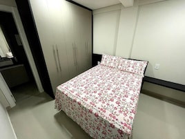 Quarto com cama, guarda-roupa e um pequeno espaço para escritório.