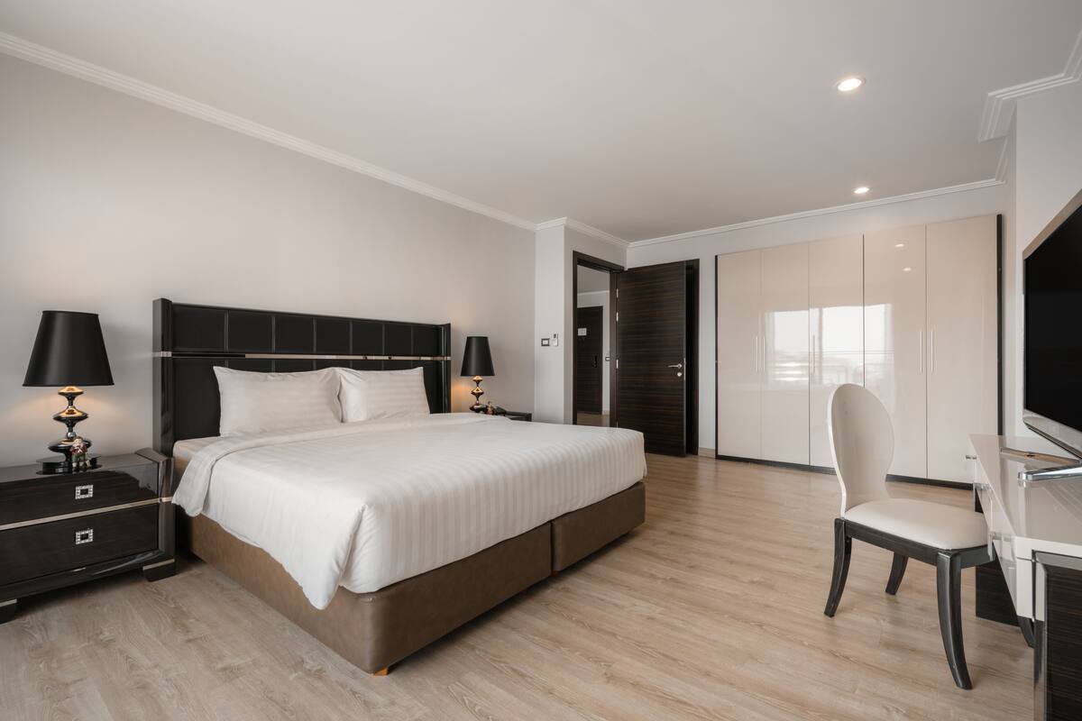 Quarto moderno com cama grande, mesas de cabeceira, escrivaninha e uma cadeira.