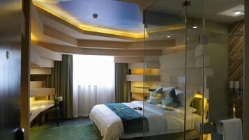 Quarto de hotel moderno com uma cama grande, uma escrivaninha e um painel de vidro.