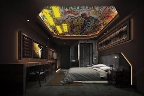 Um quarto moderno com claraboia com tema de grafite, uma escrivaninha e uma cama com mesa de cabeceira.