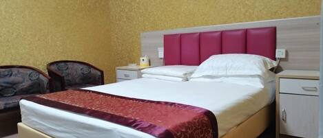 Quarto de hotel com cama, mesa de cabeceira, cadeira e guarda-roupa.