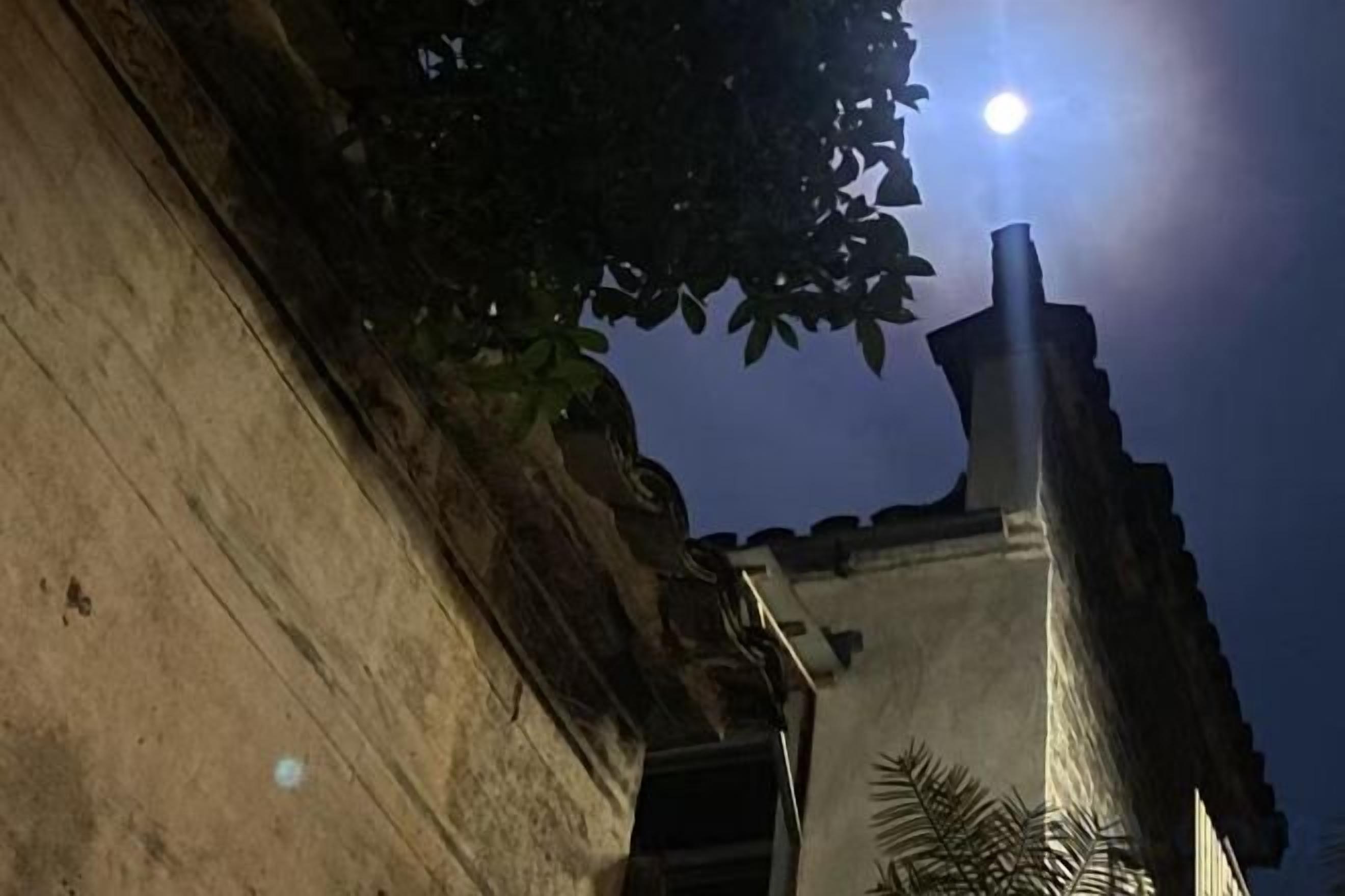 Um edifício sob um céu iluminado pela lua, com chaminé e porta.