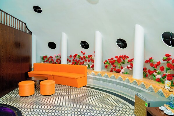 Um hall moderno com área de estar curva, escada de madeira e arranjos florais decorativos.