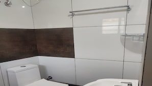Casa de banho com sanita, lavatório e suporte para toalhas.