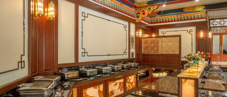 Um hall de hotel com design tradicional, apresentando um balcão de recepção de mármore, painéis decorativos na parede e um teto padronizado.