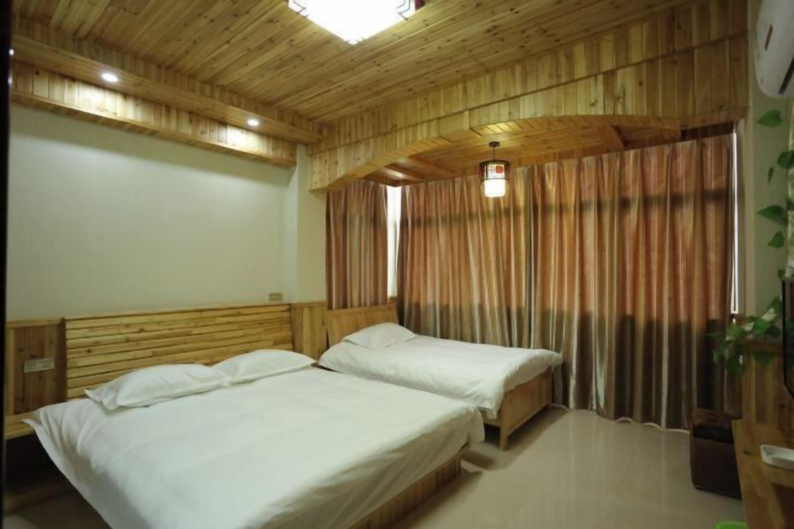 Quarto com duas camas de madeira, teto de madeira e janela com cortinas.
