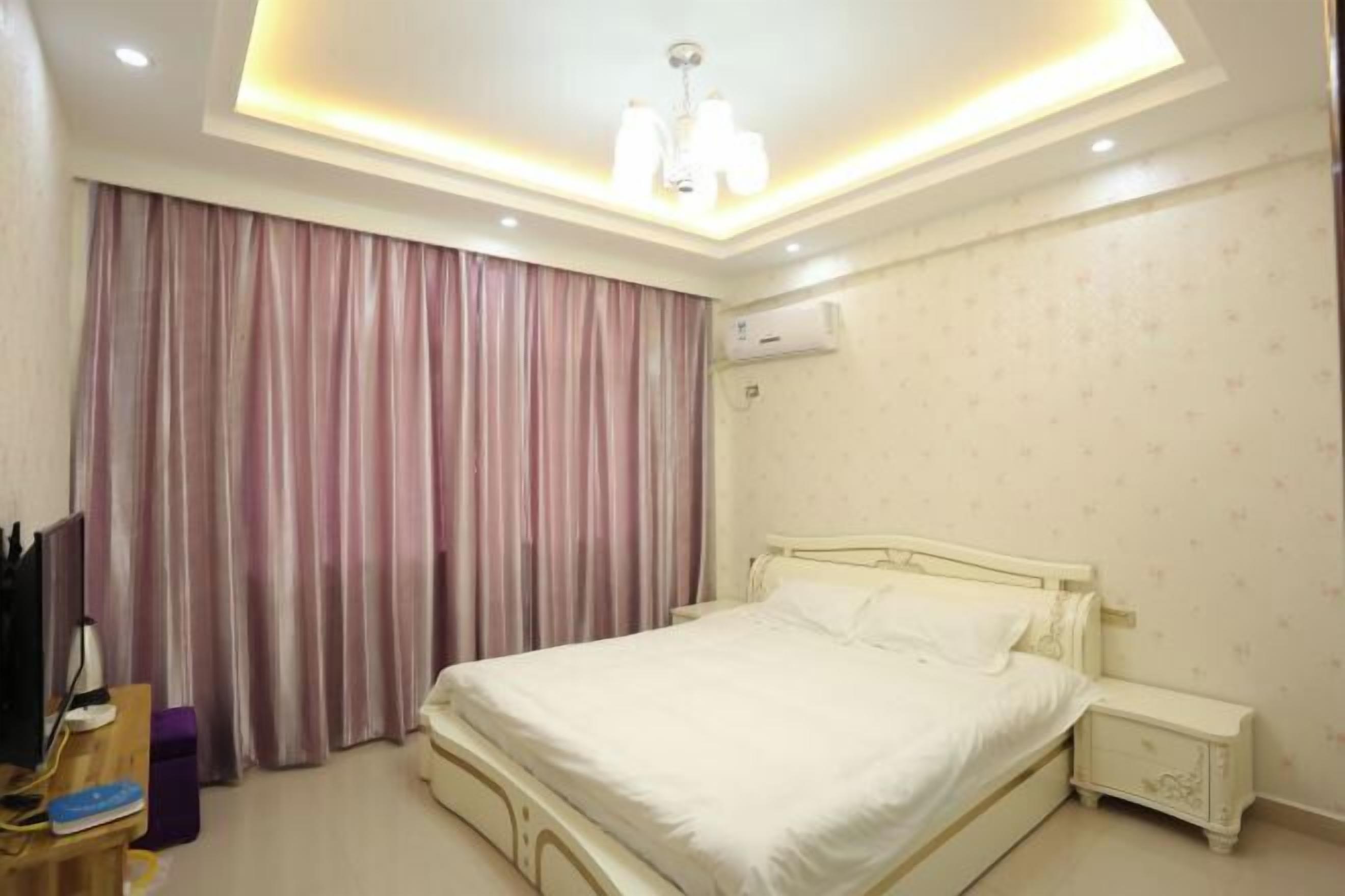 Quarto com cama, cortinas, ar condicionado, mesa de cabeceira e televisão.
